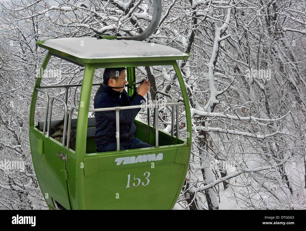 Henan. 18th Feb, 2014. A tourist takes photos of snow scenery from a ...