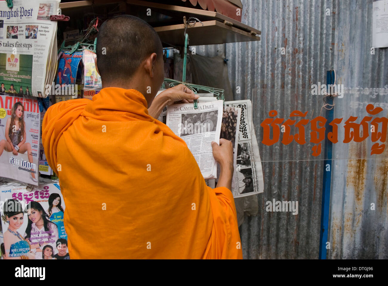 A Buddhist monk is reading a Cambodia Daily newspaper at a news stand ...