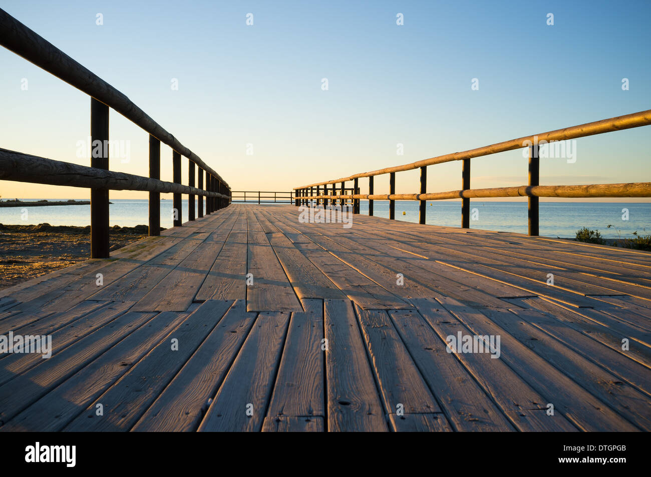 Wooden jetty under the golden light of sunrise Stock Photo - Alamy