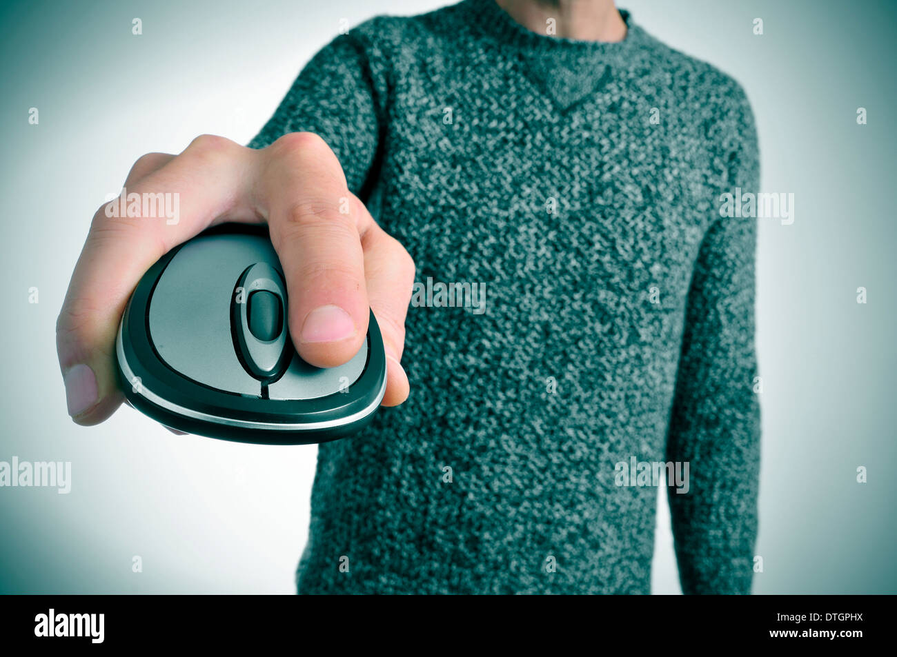 a young man in casual wear pointing a computer mouse to the foreground ...