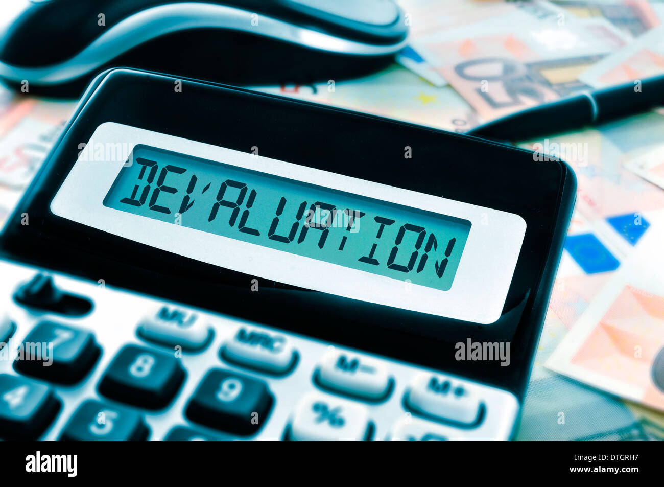 word devaluation on the display of a calculator with euro bills in the ...