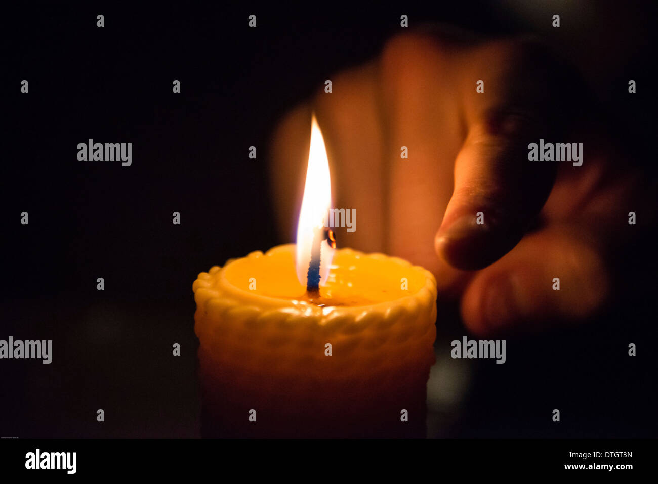 Finger next to a burning wax candle Stock Photo - Alamy