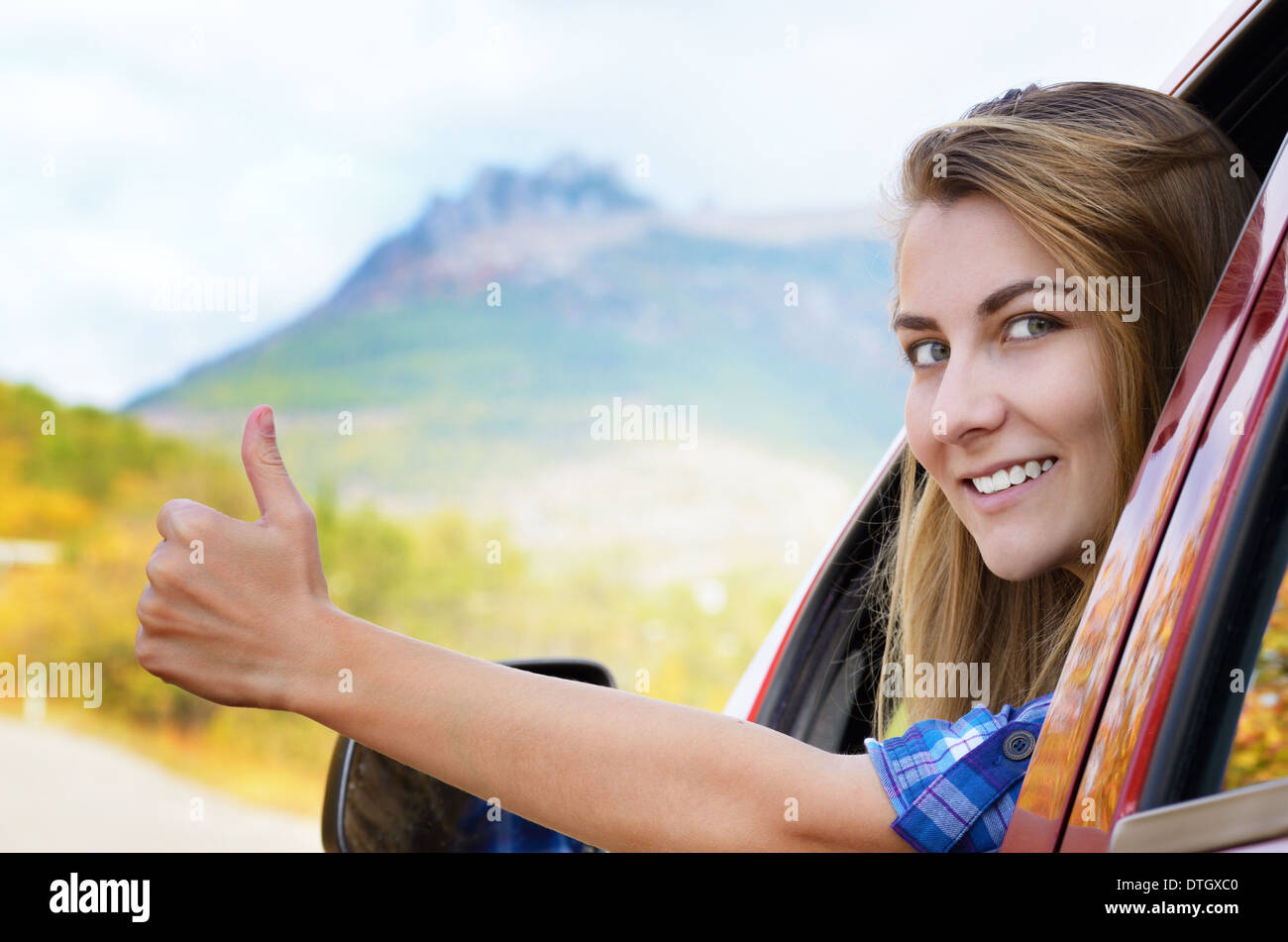 Happy driver woman shows thumb up against mountains background. Car ...