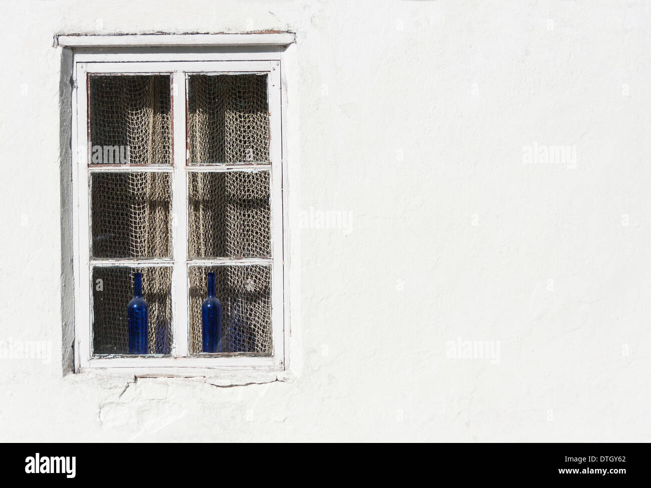 Window with two blue wine bottles and fishing net in white wall Stock ...
