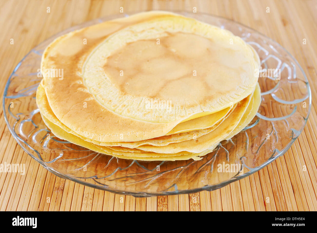 Pile of homemade delicious crepes on a glass plate, bamboo mat ...