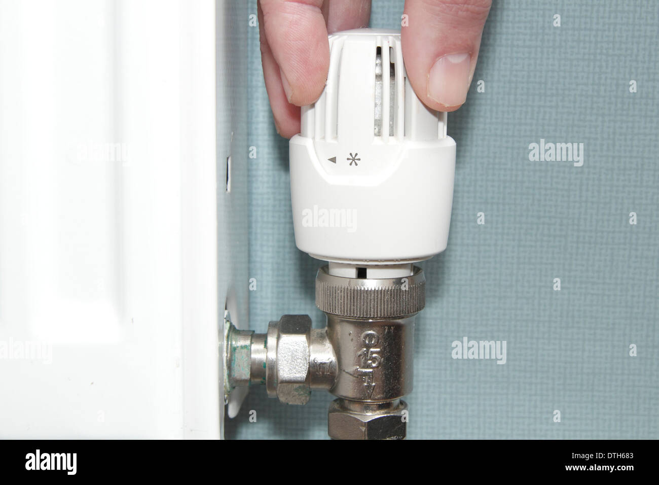 Man turning radiator valve/heating control up down in lounge of ...