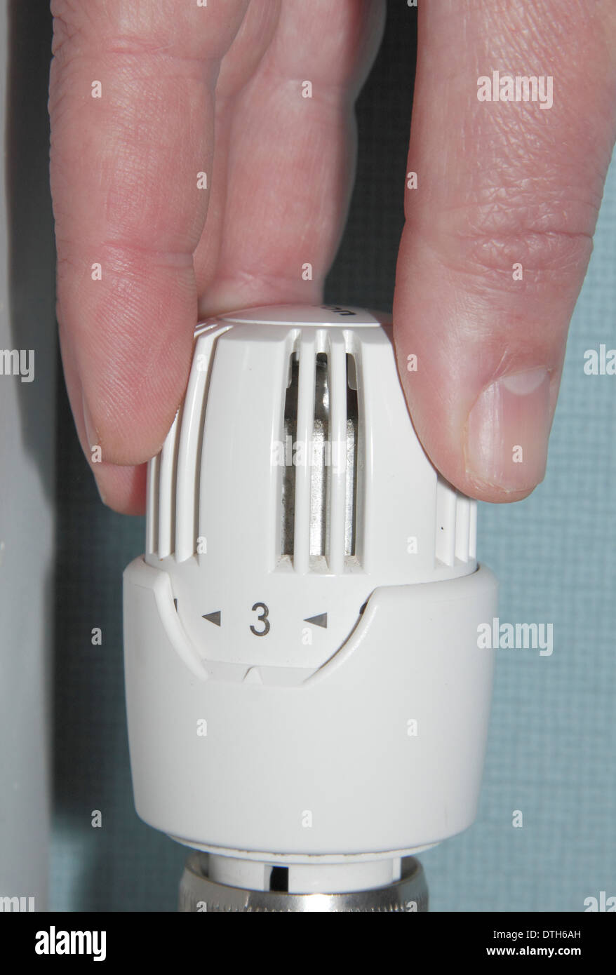 Man turning radiator valve/heating control up down in lounge of ...