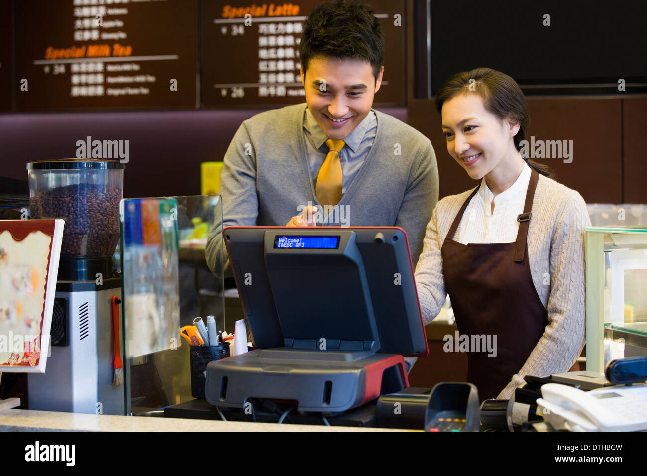 Coffee store shopkeeper and waitress using cash register Stock Photo ...