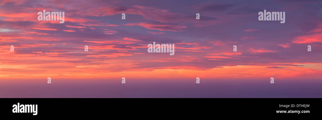 Fire red high cirrus clouds over the sea horizon at sunset. View from ...