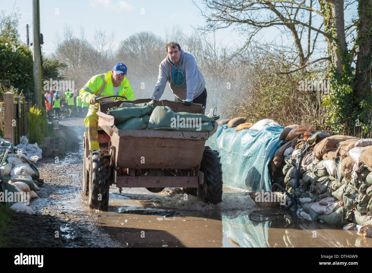 Volunteer aid workers help distribute sandbags in the flooded village ...