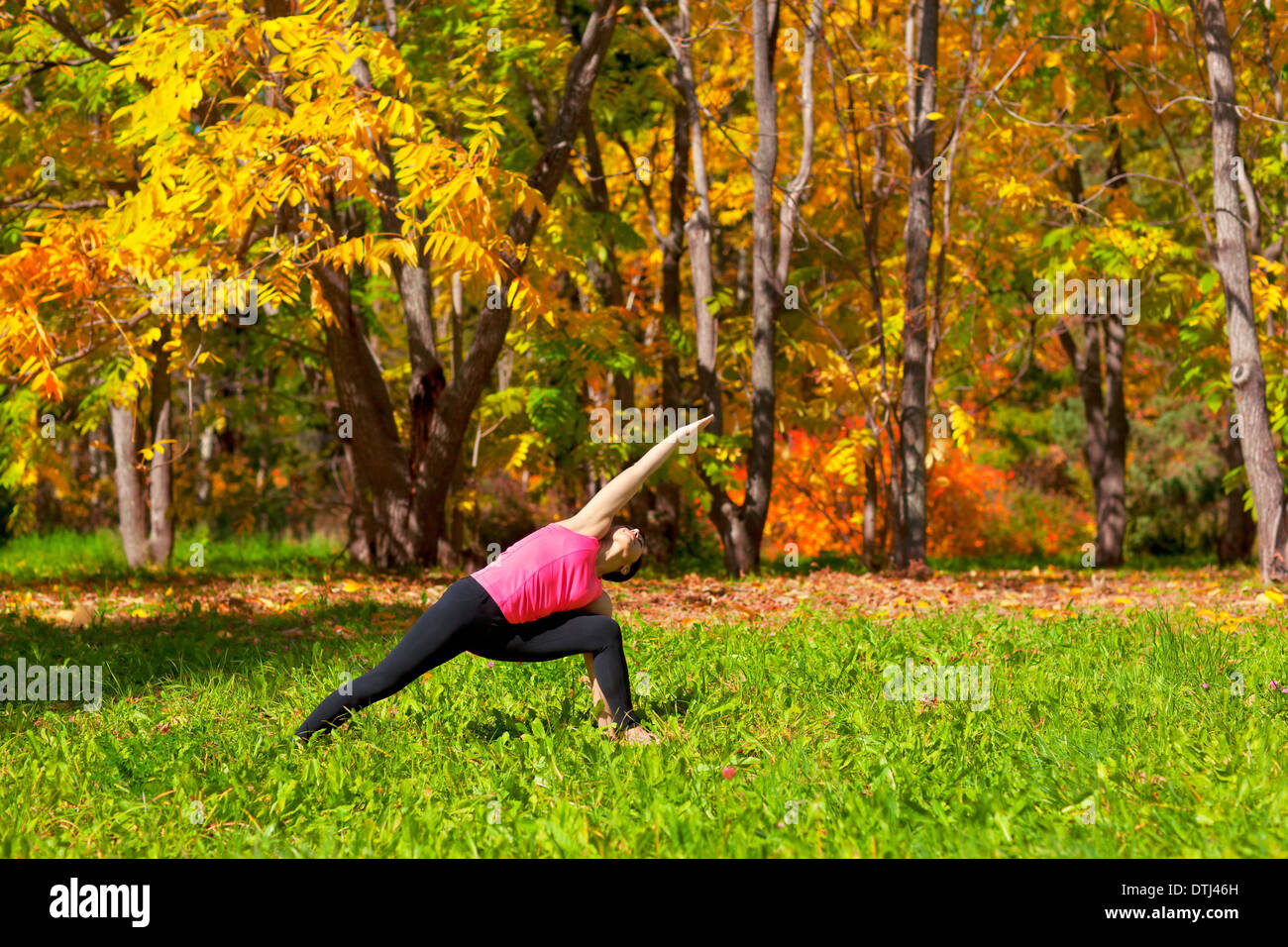 Woman exercises in the autumn forest yoga utthita parshvakonasana pose ...