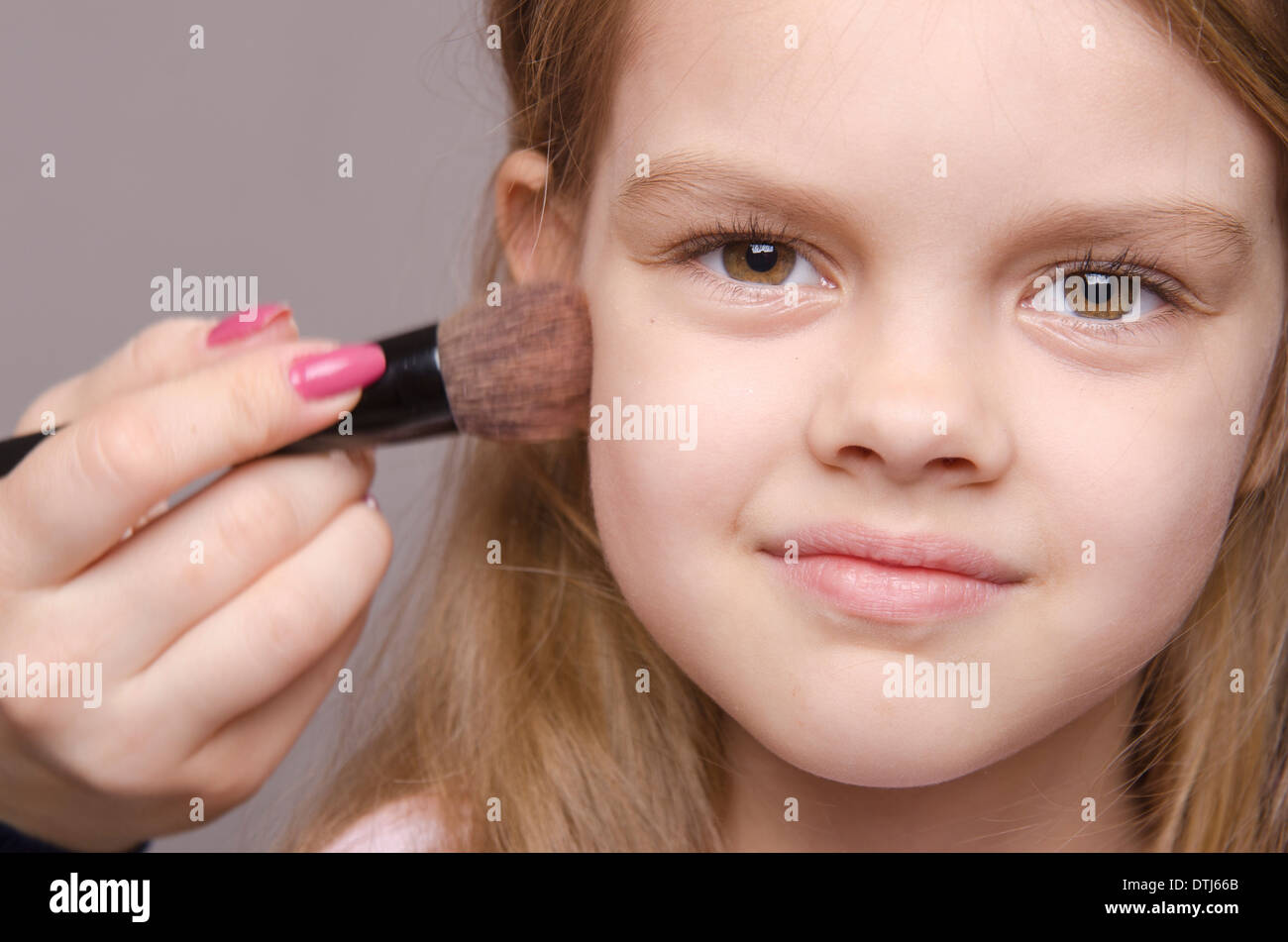 Makeup artist deals powder brush on the face of a five year old girl ...