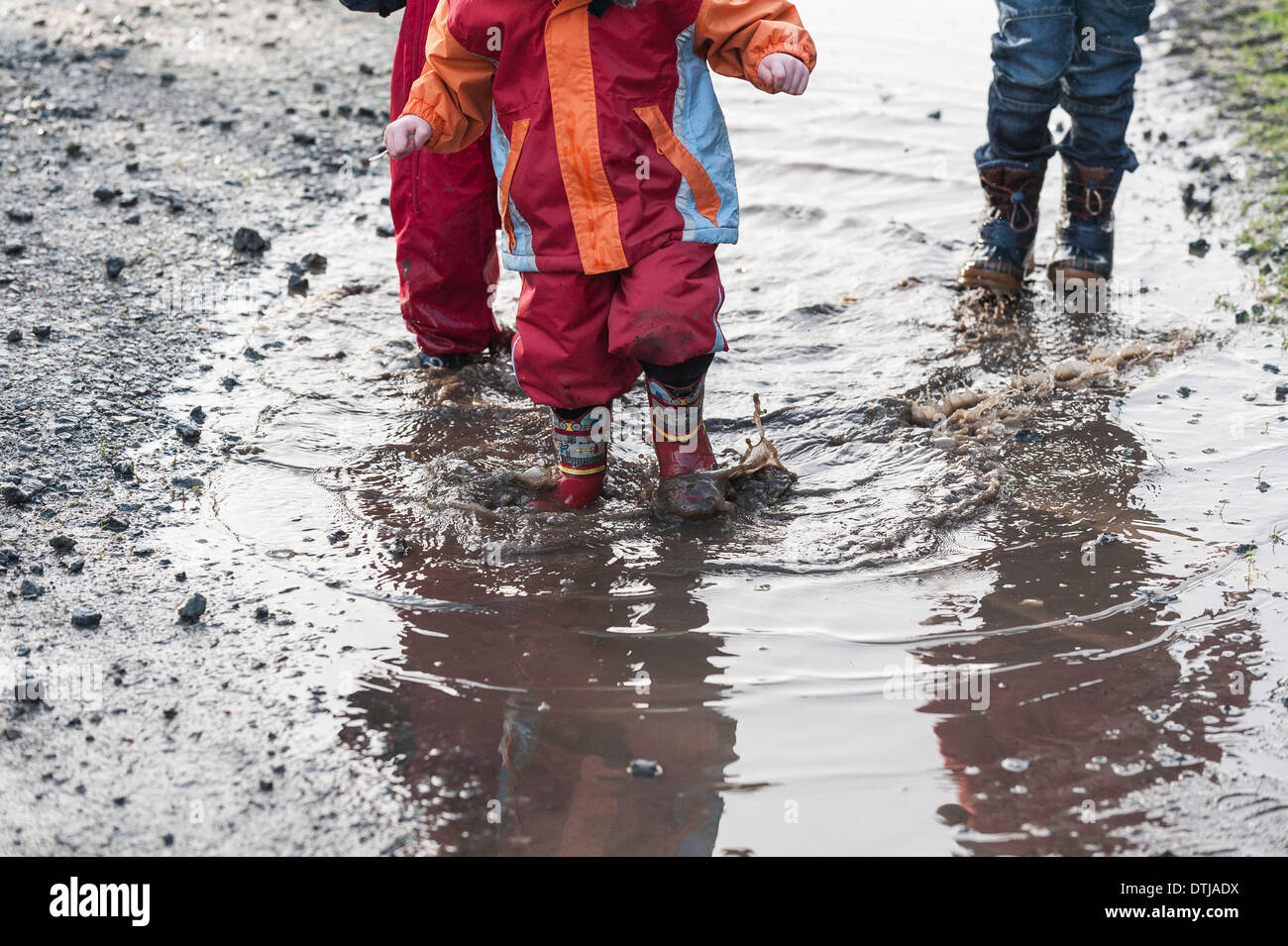 Toddlers splashing through a puddle Stock Photo - Alamy