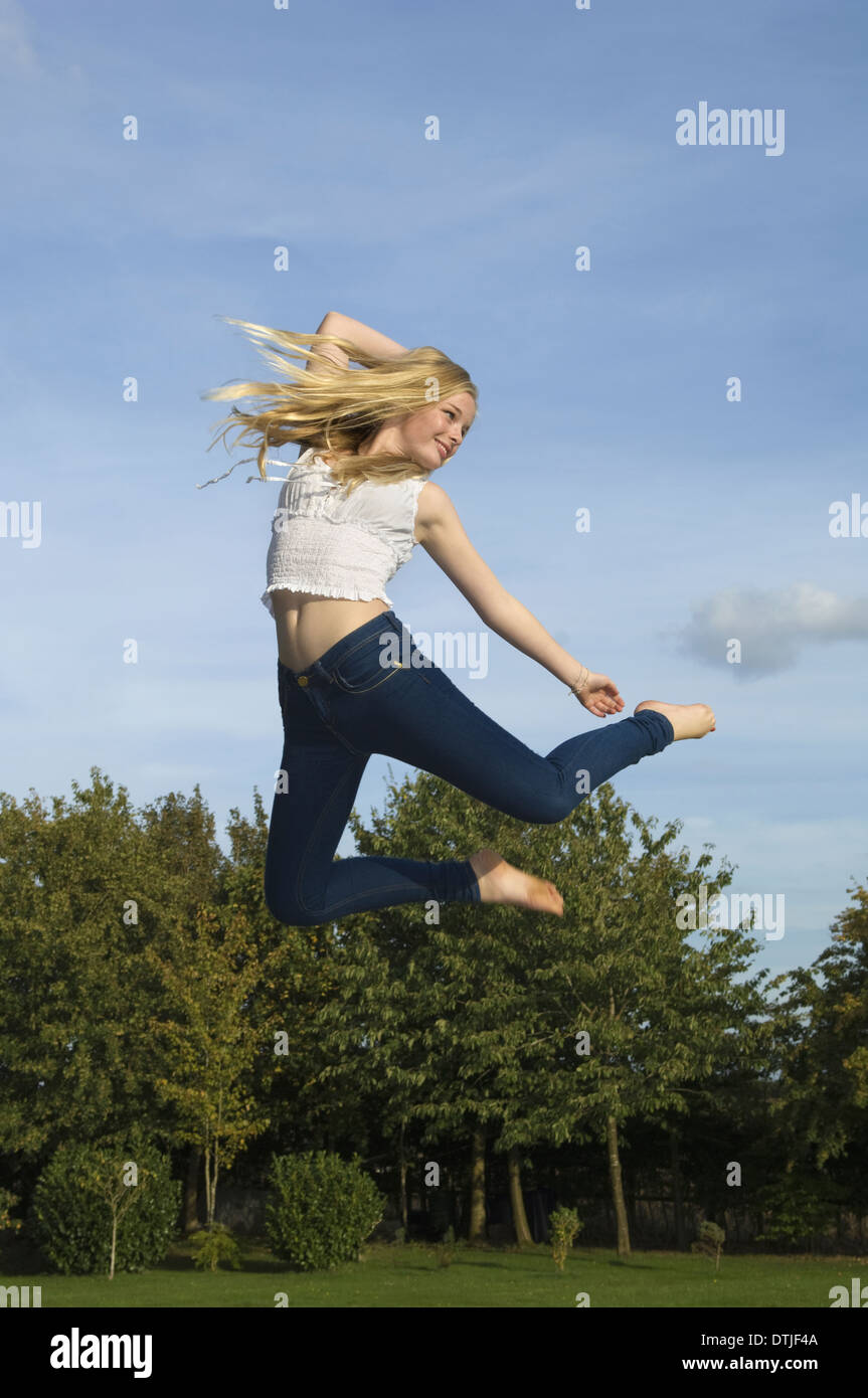 Teenage girl with long blond hair jumping in the air Gloucestershire ...