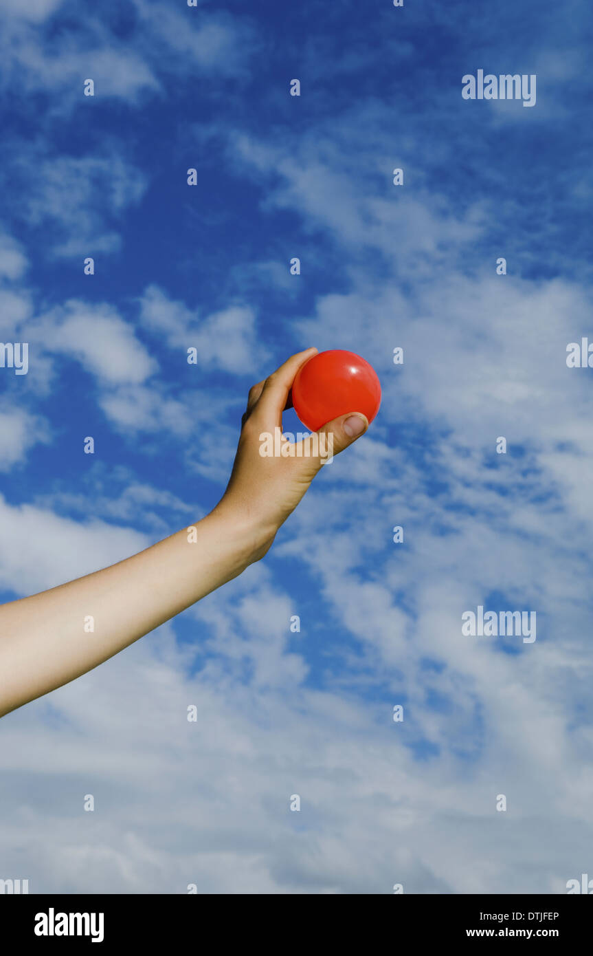 A person's outstretched hand holding a red ball Gloucestershire England ...