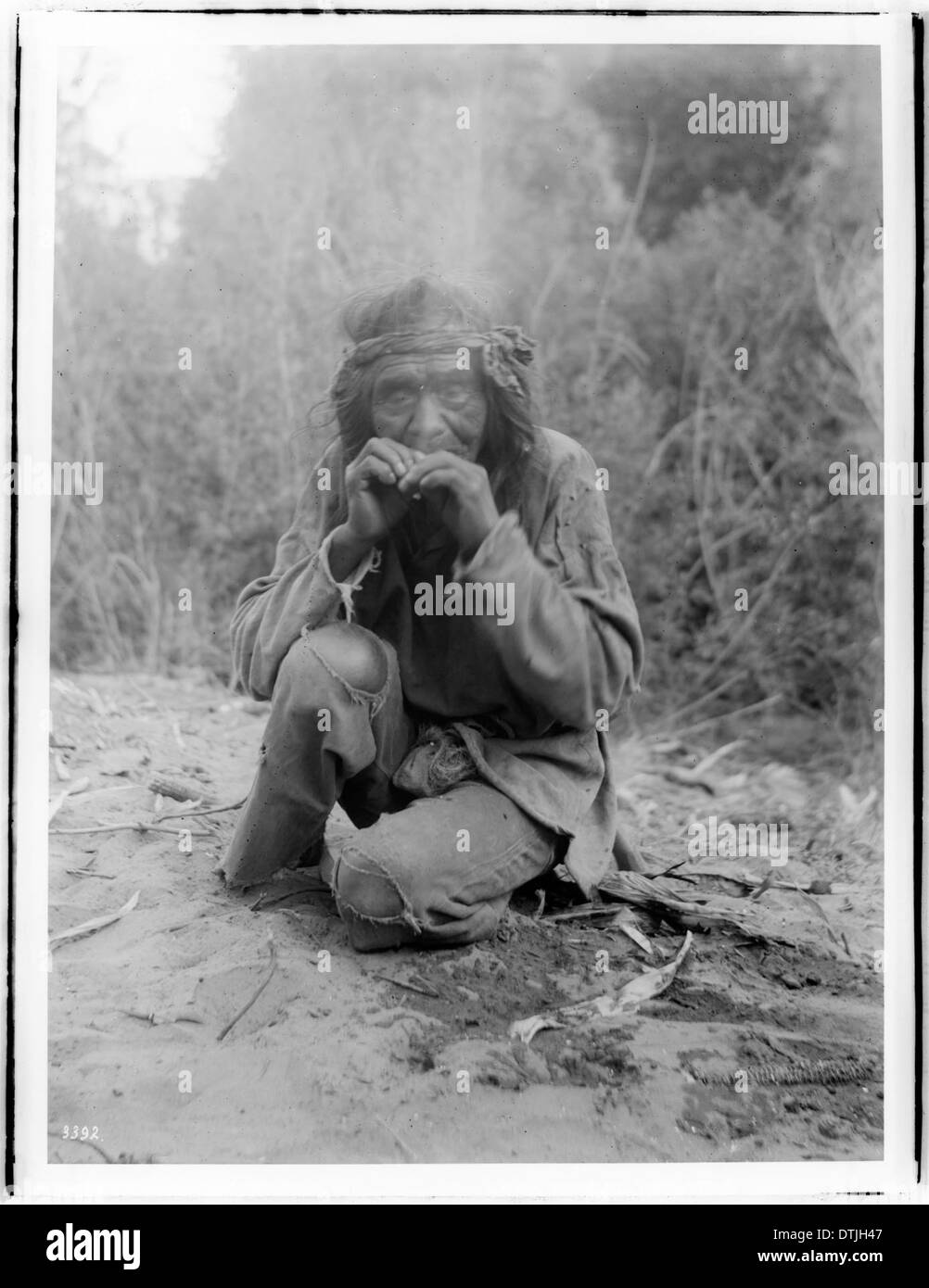 An elderly Havasupai Indian man is photographed crouching on the ground ...