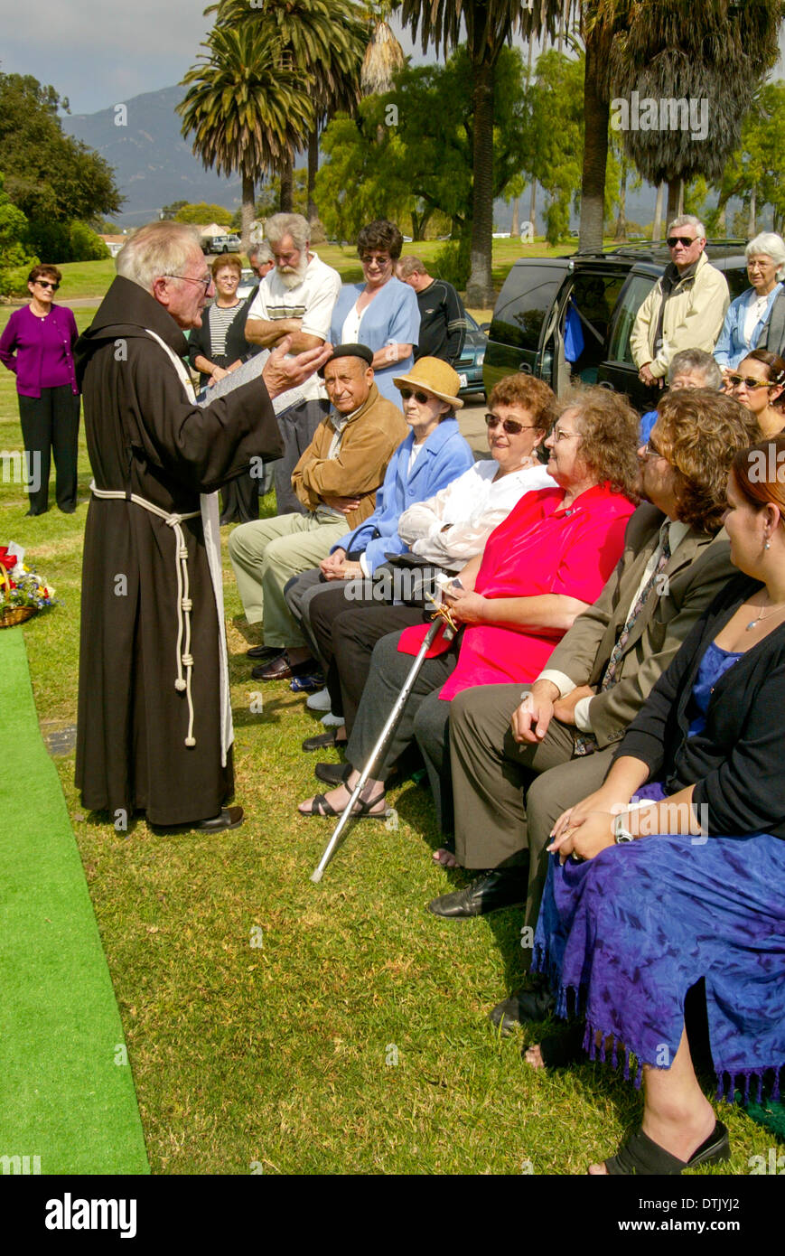 A robed Franciscan priest speaks with family members after officiating ...