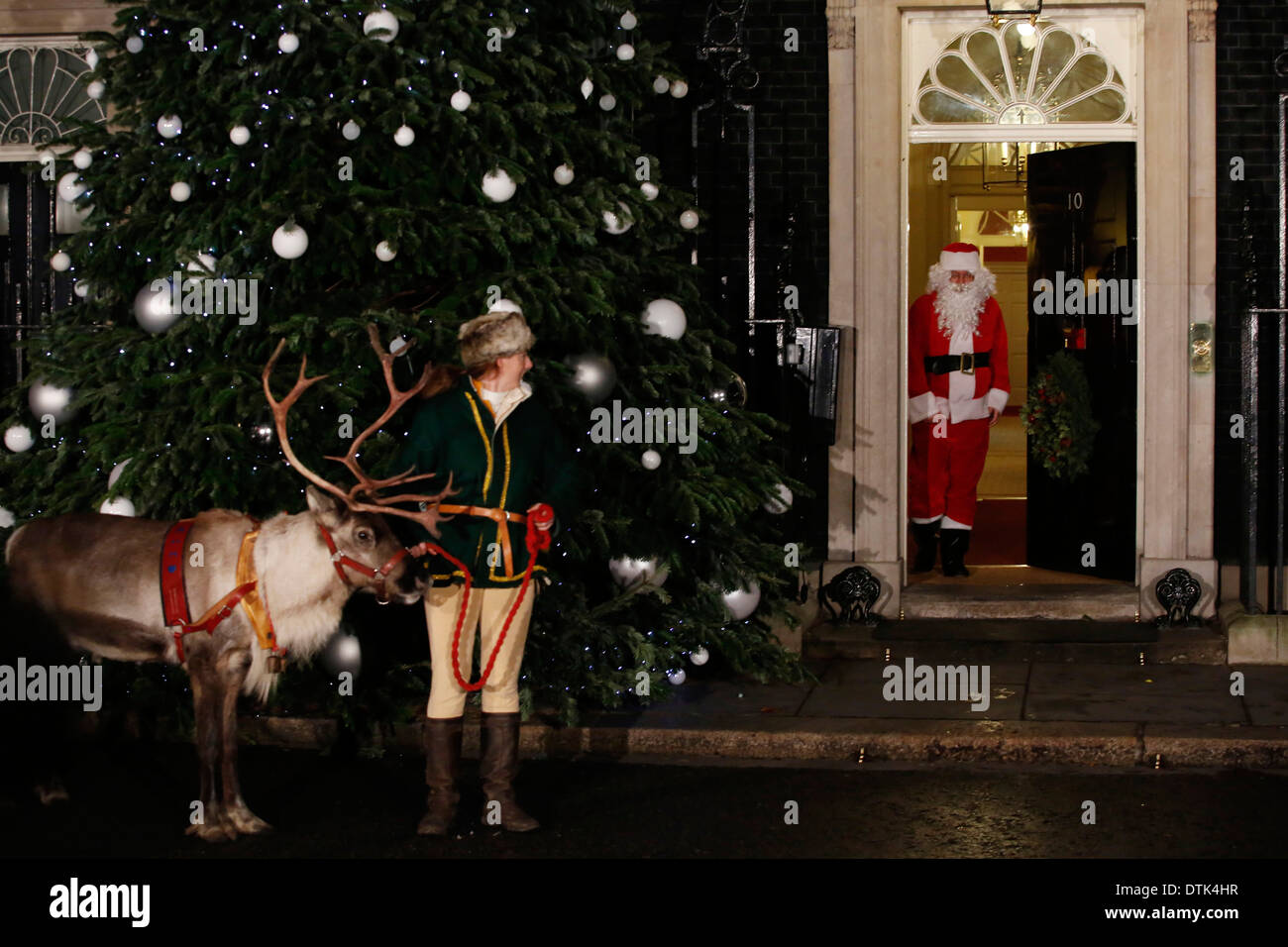 Santa Claus walks out of the front door when reindeer walk in line past ...