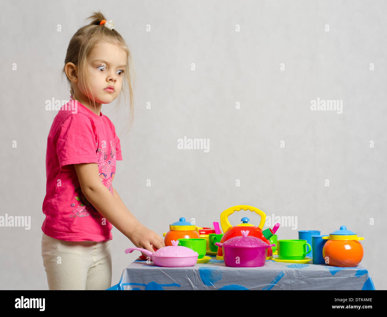 Girl plays child kitchen utensils. The girl is left of the table and ...