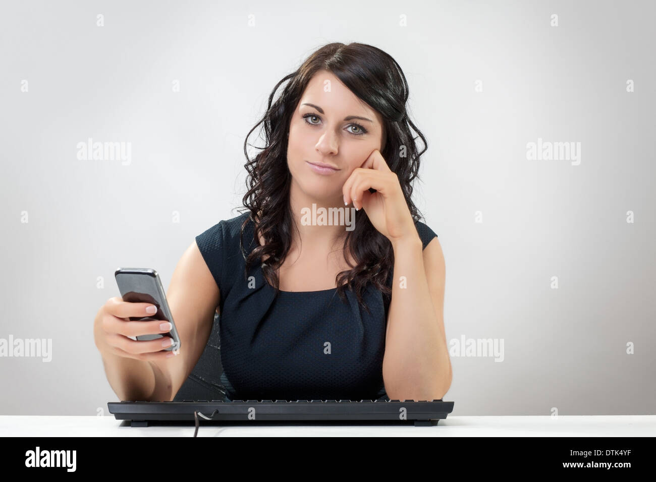 woman sitting at her desk working on her computer and texting on her ...