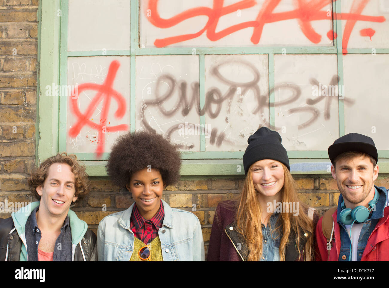 Friends smiling together in front of graffiti window Stock Photo - Alamy