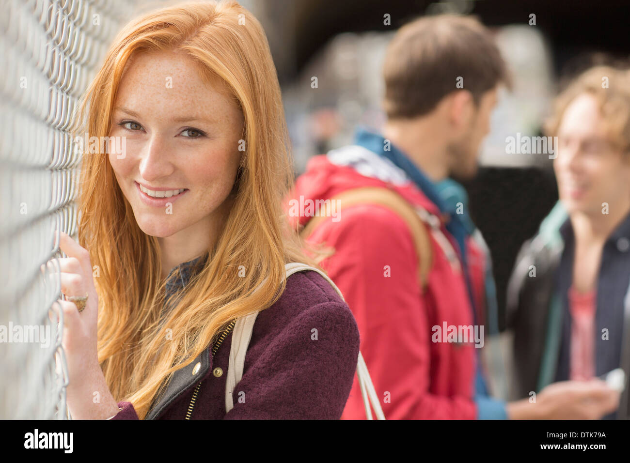 Woman smiling by chain link fence Stock Photo - Alamy