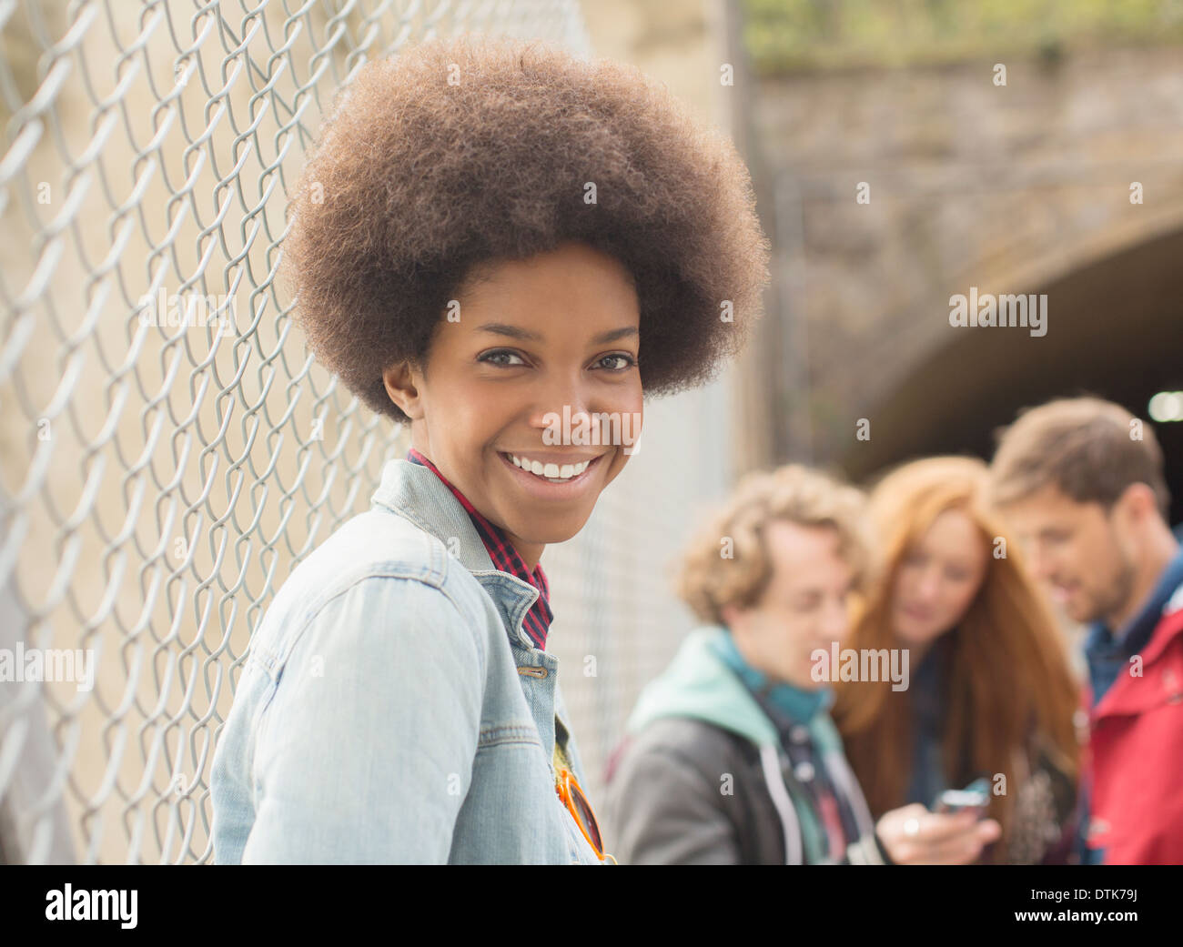 Woman smiling by chain link fence with friends in background Stock ...