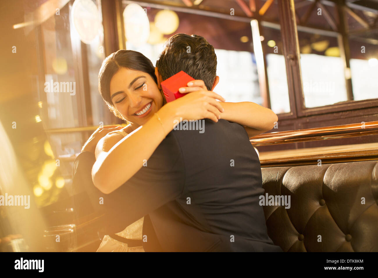Woman with jewelry box hugging man in restaurant Stock Photo - Alamy
