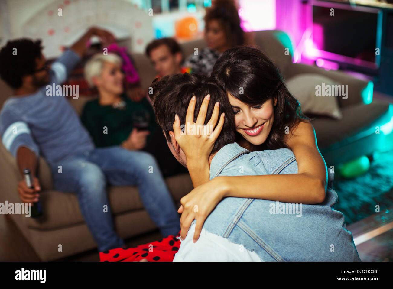 Couple hugging in living room at party Stock Photo - Alamy