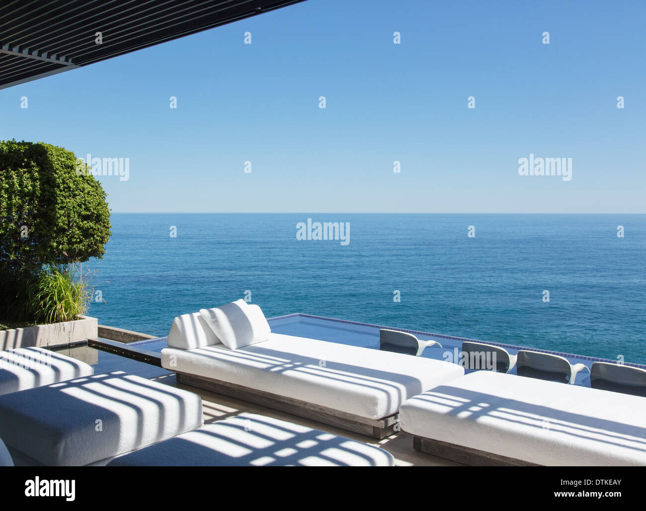 Sofas and infinity pool overlooking ocean Stock Photo - Alamy