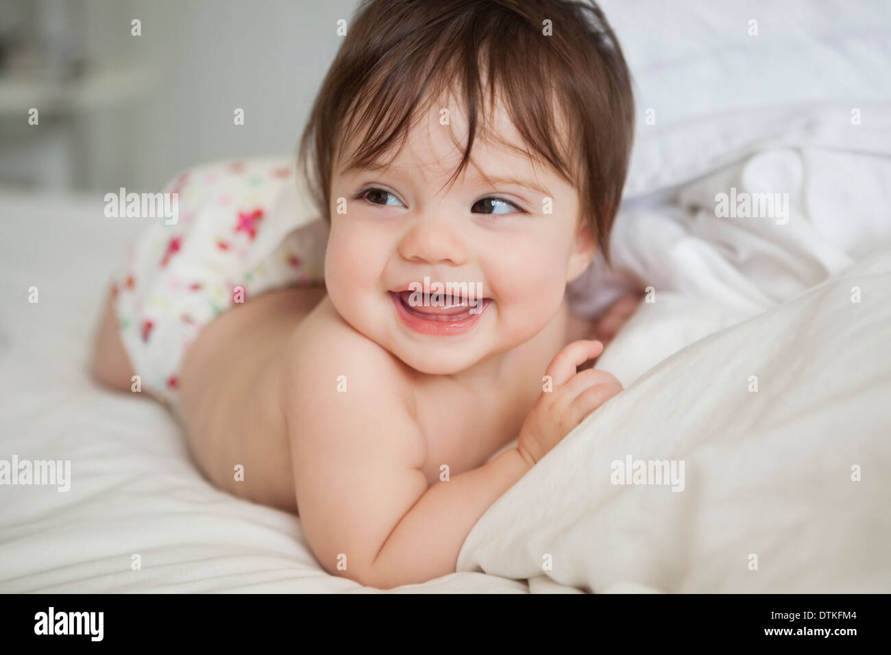 Baby girl laying in bedsheets Stock Photo - Alamy