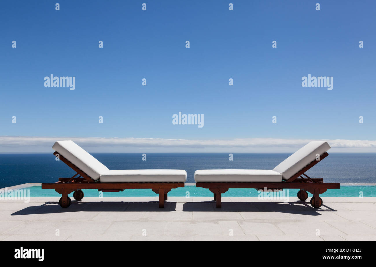 Lounge chairs and infinity pool overlooking ocean Stock Photo - Alamy