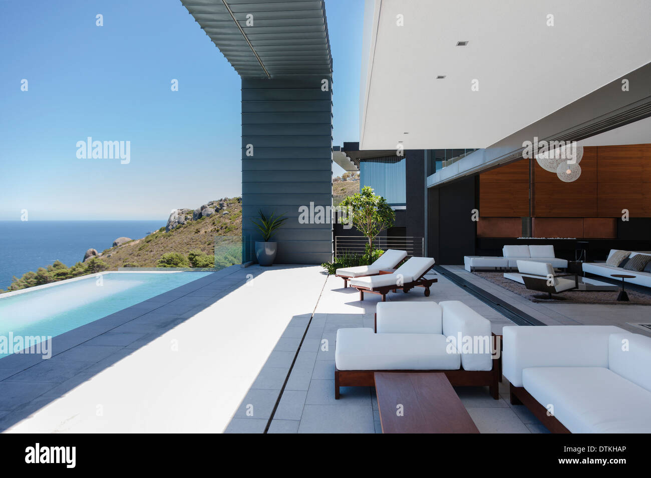 Lounge chairs and infinity pool on modern patio overlooking ocean Stock ...