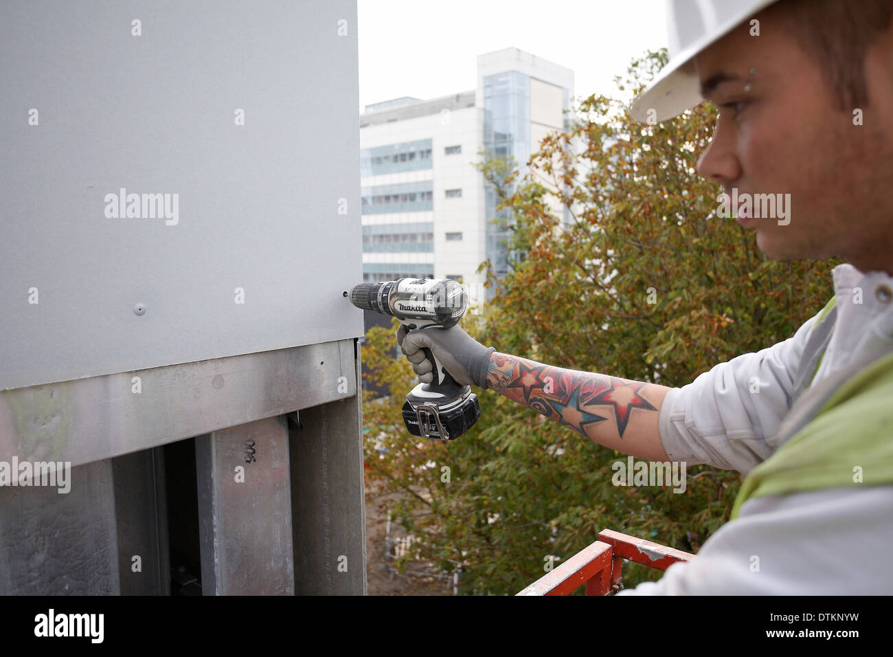 Workman securing insulation cladding and paneling at Swansea university ...