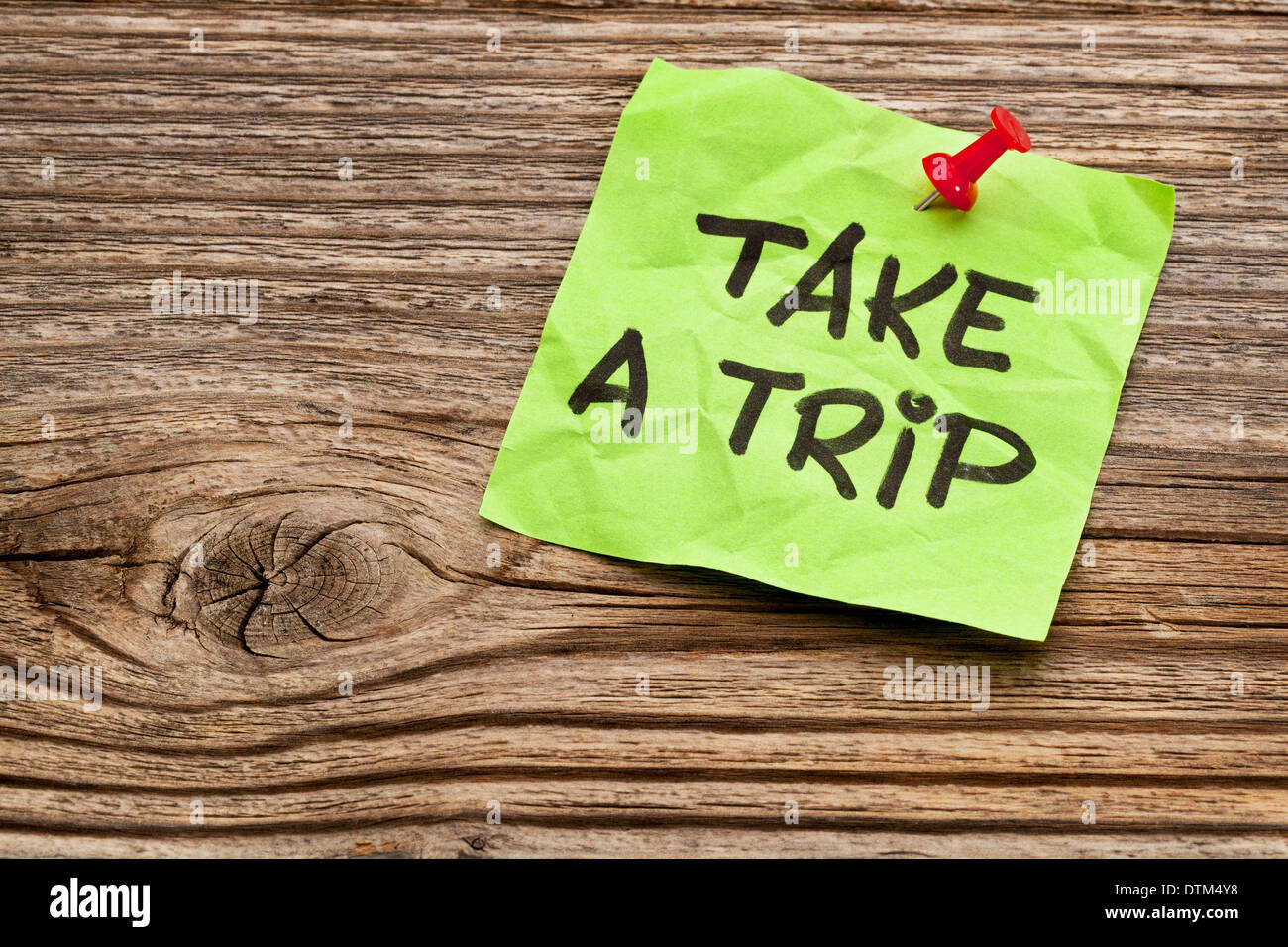 take a trip - handwriting reminder note on a green sticky note against ...