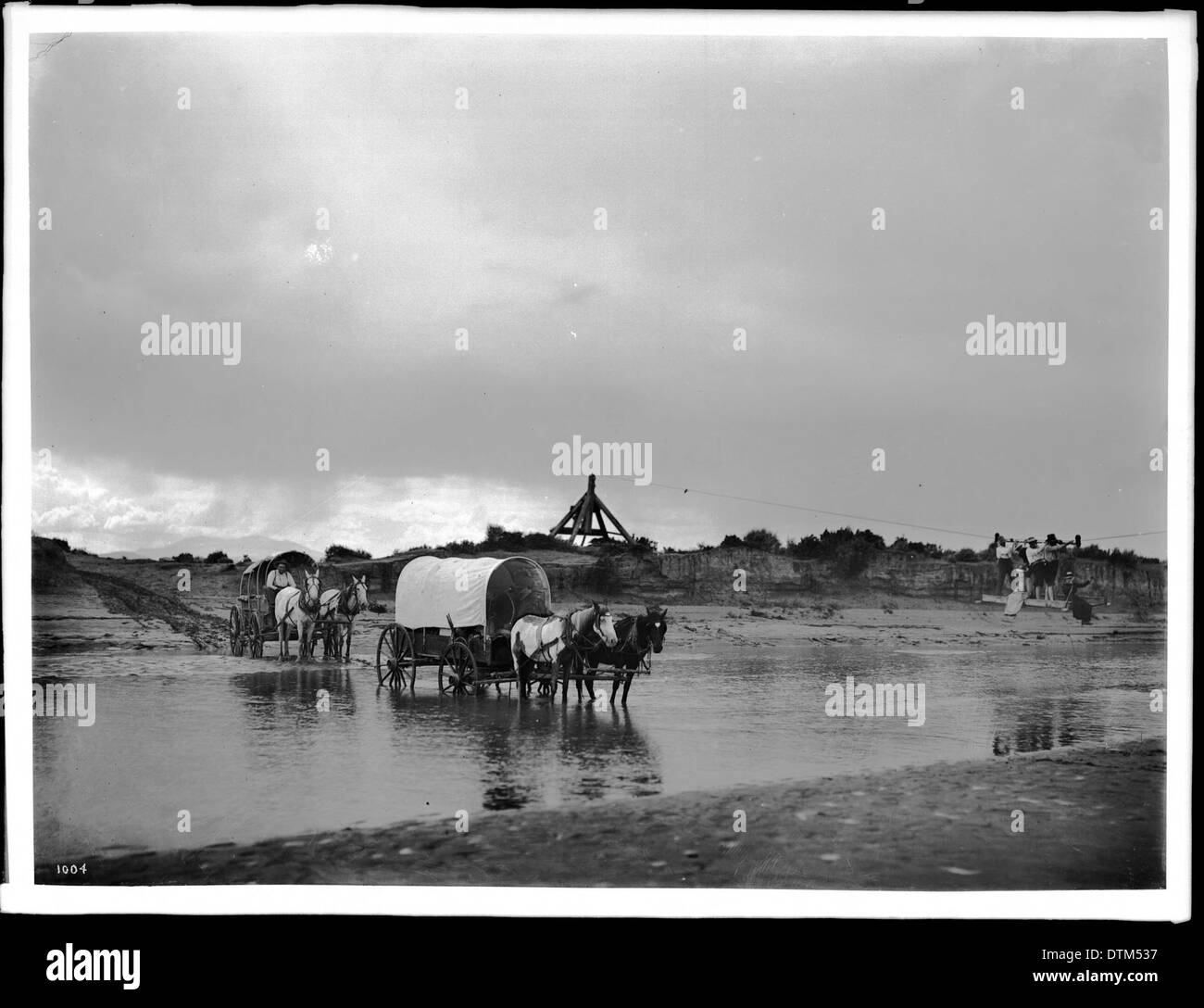 Two covered wagons are seen fording the Little Colorado River next to a ...