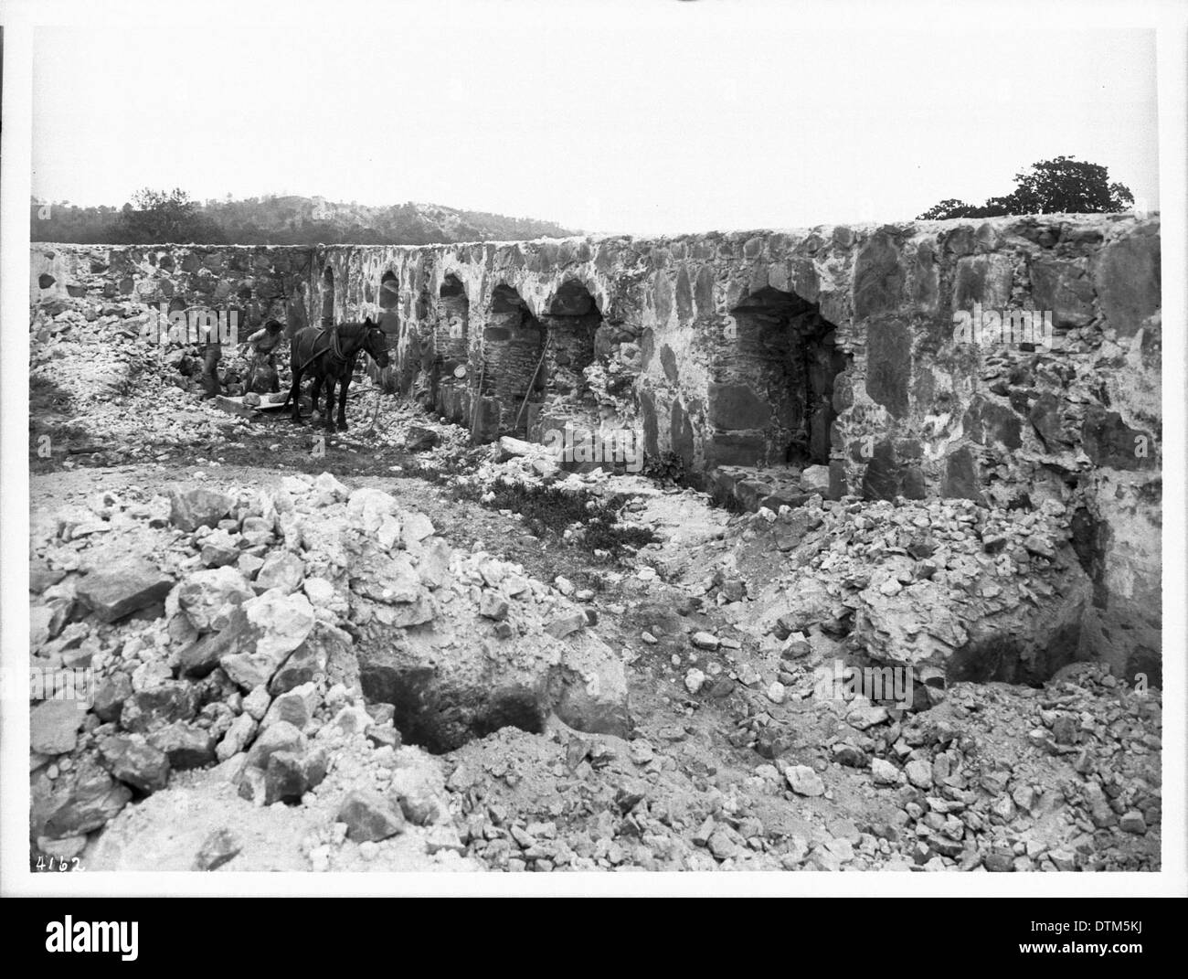 Two men are photographed working to remove stones from the ruins of ...