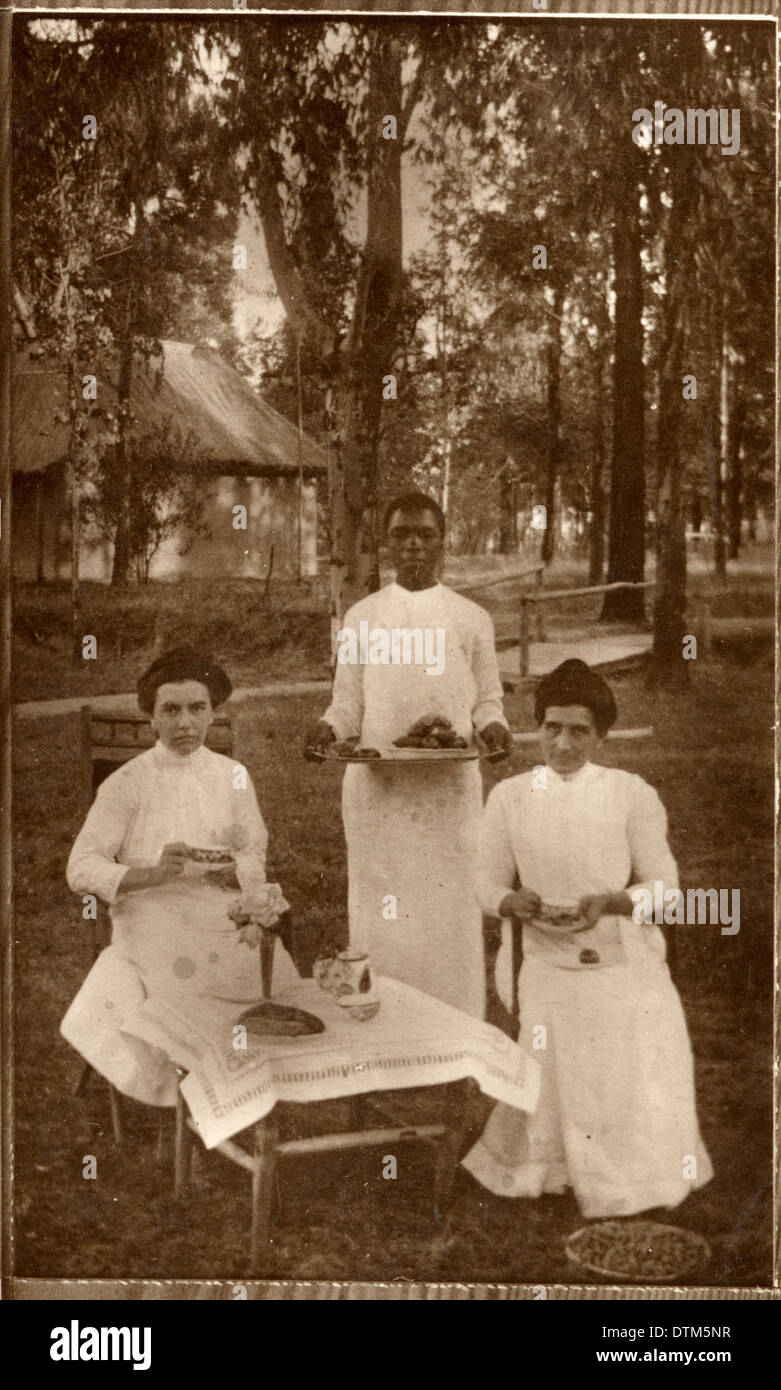 A photograph depicting two missionary women being served tea outdoors ...