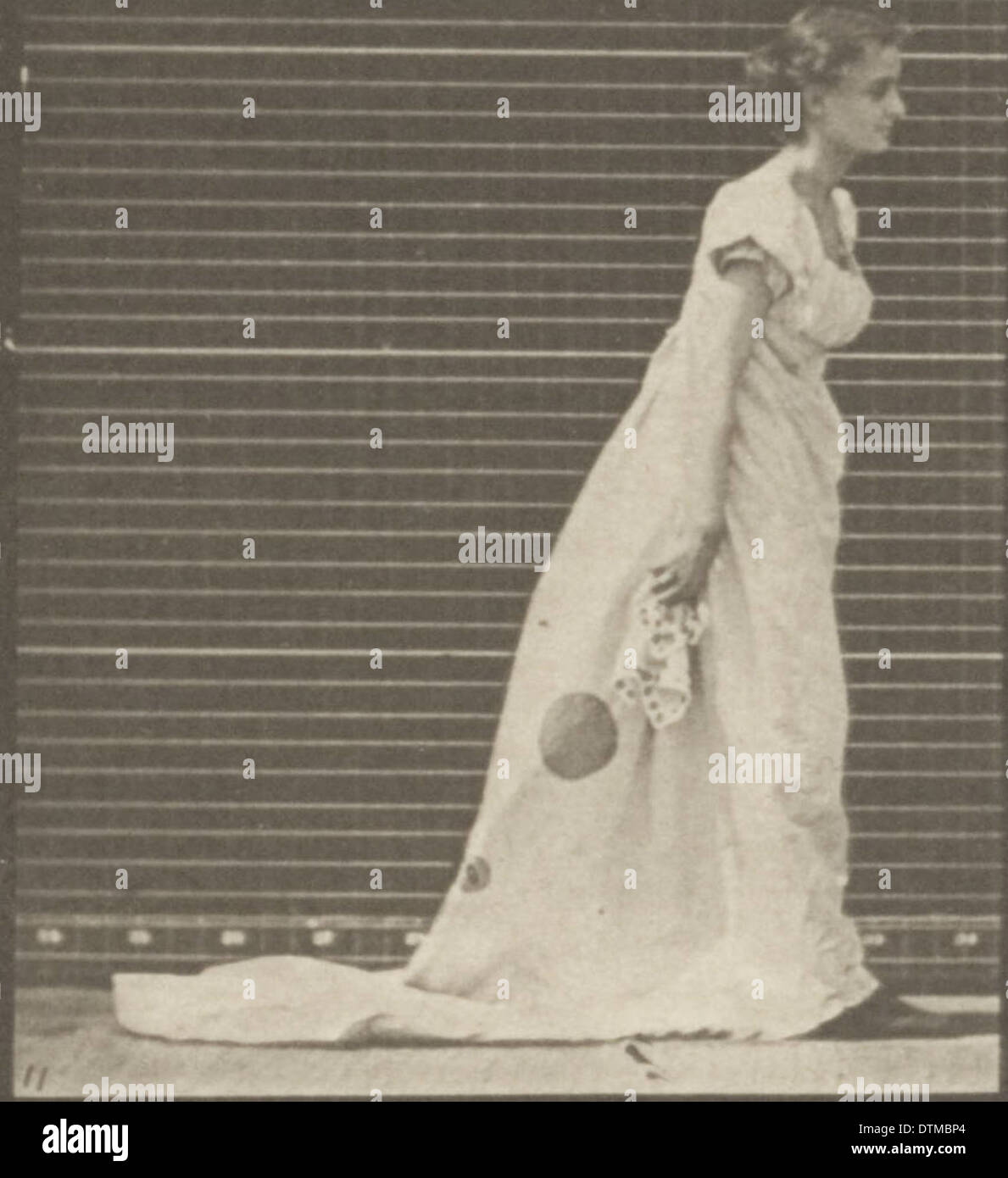 A woman in a long dress is stooping and lifting a handkerchief ...