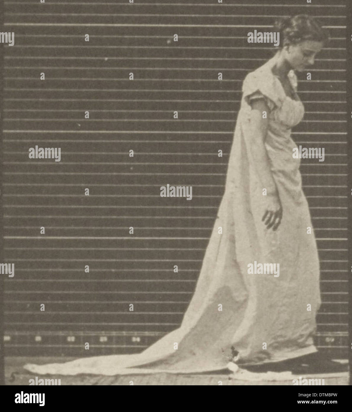 A woman in a long dress is photographed stooping to lift a handkerchief ...