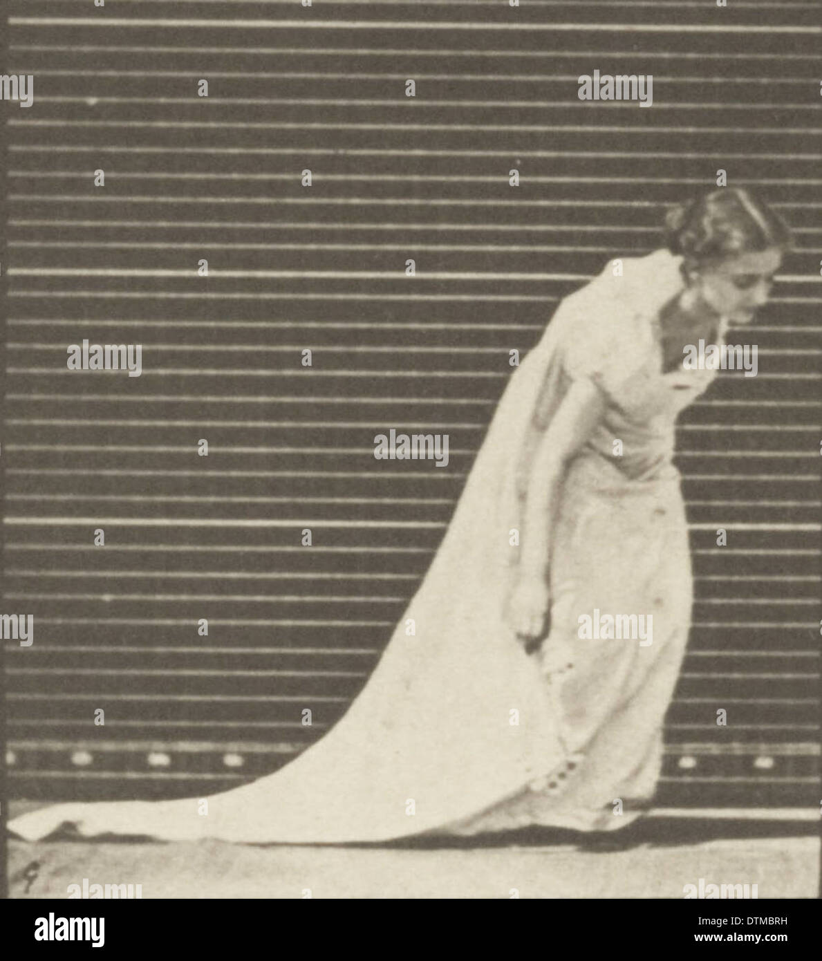 A woman in a long dress is captured stooping to lift a handkerchief ...