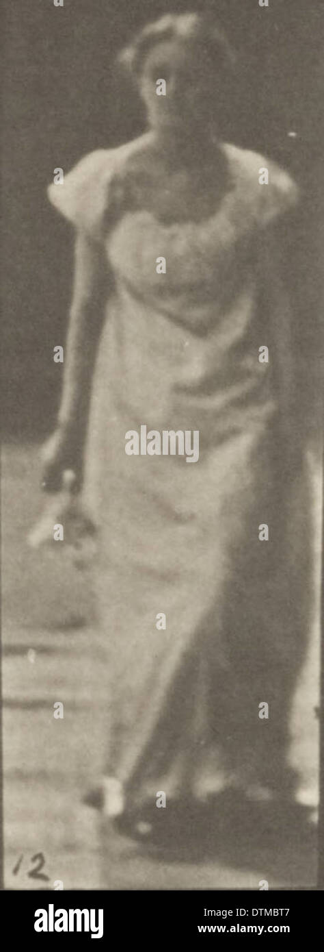 A photograph of a woman in a long dress stooping and lifting a ...