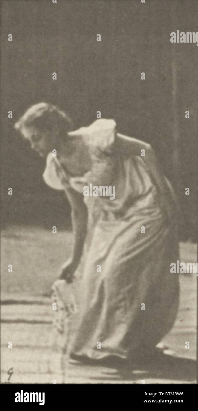 A woman in a long dress is photographed stooping and lifting a ...