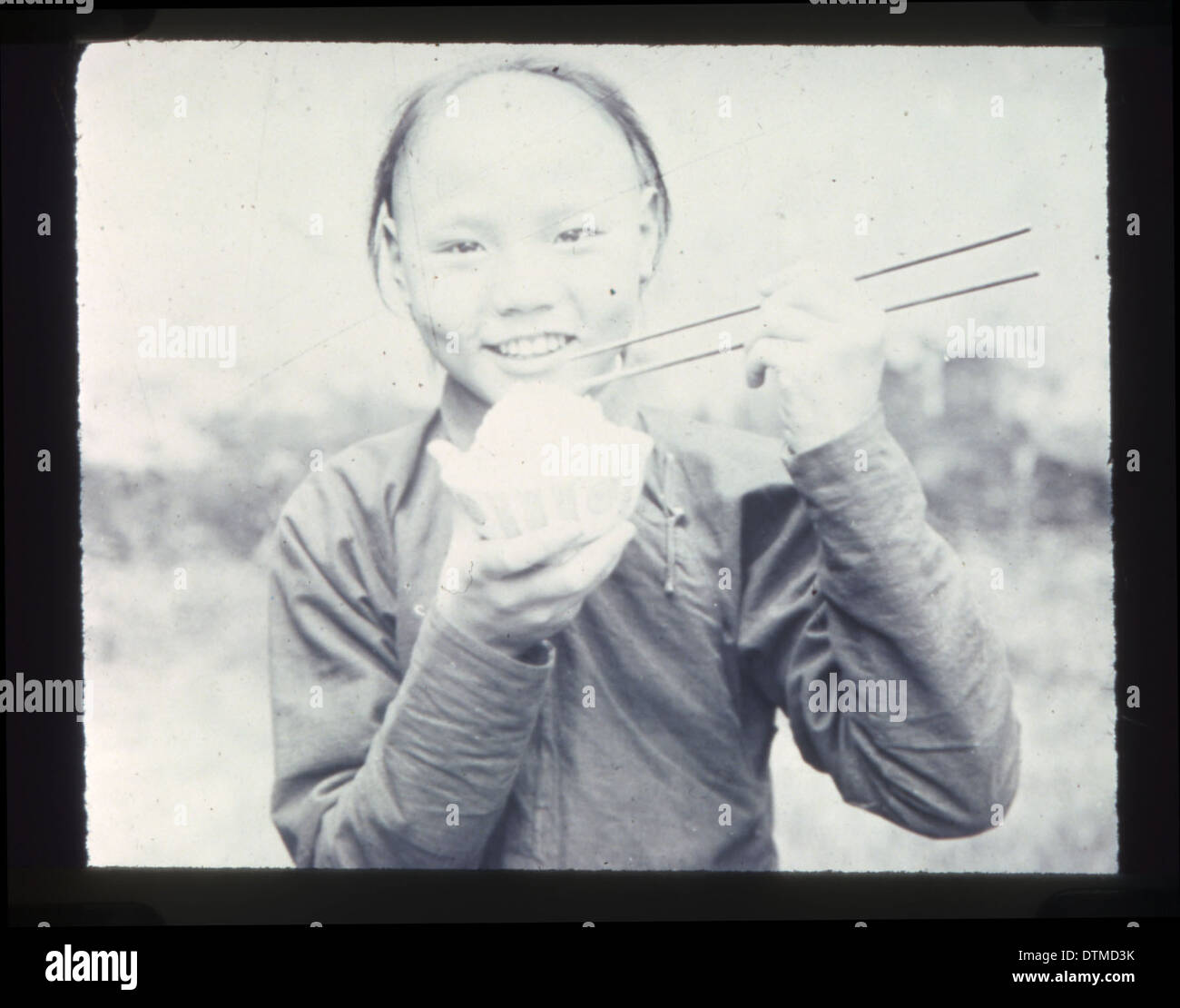 A young Chinese person is shown eating rice with chopsticks, taken in ...