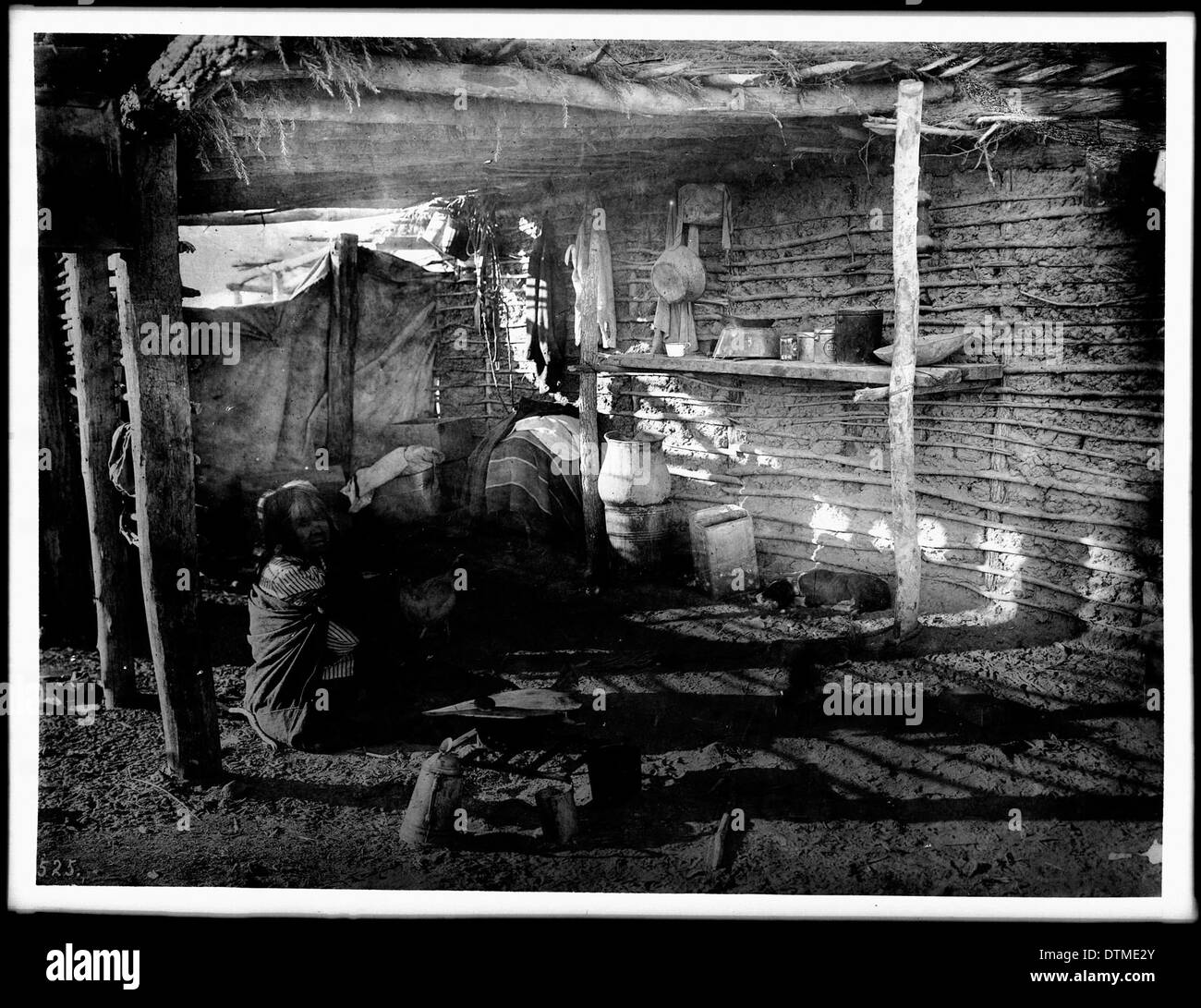 A Yuma Indian woman sitting in the shadow of a ramada, near her cooking ...