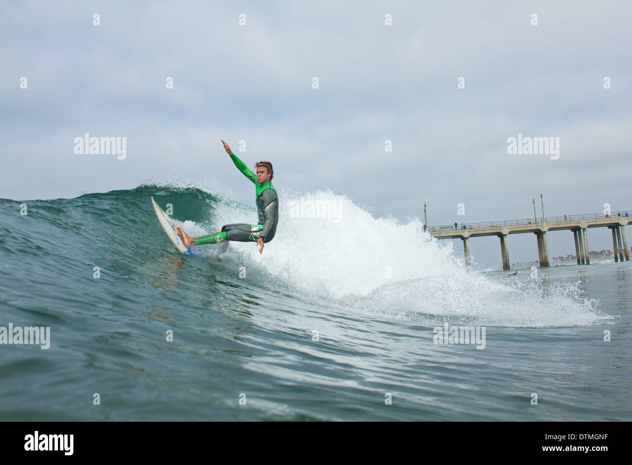surfer in wet suit on a surfboard riding a wave by the pier Stock Photo ...