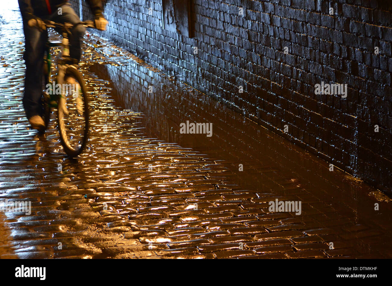 Cyclist speeding through the canal underpass, on the old cobbles Stock ...