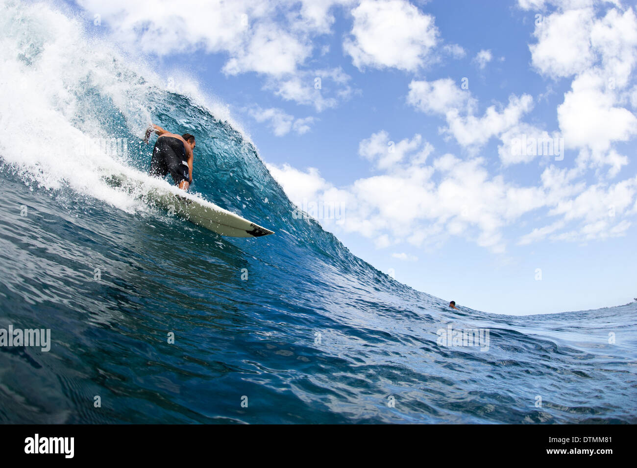 male surfer surfing in hawaii inside a barrel of water with clouds in ...