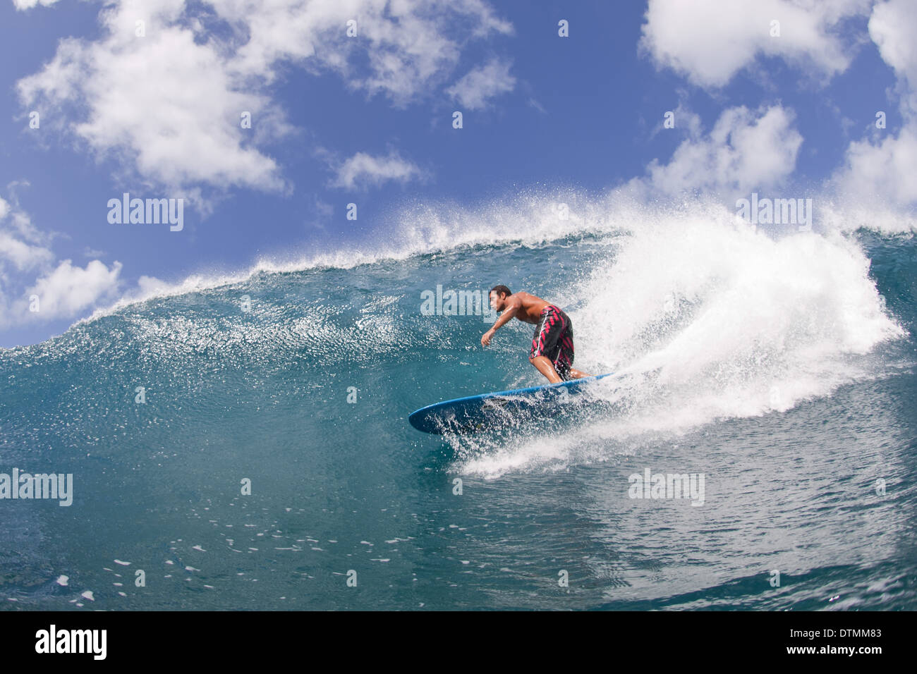 male surfer surfing in hawaii inside a barrel of water with clouds in ...