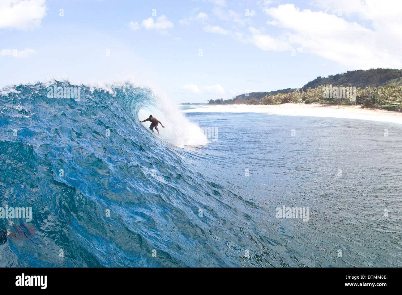 male surfer surfing in hawaii inside a barrel of water with clouds in ...